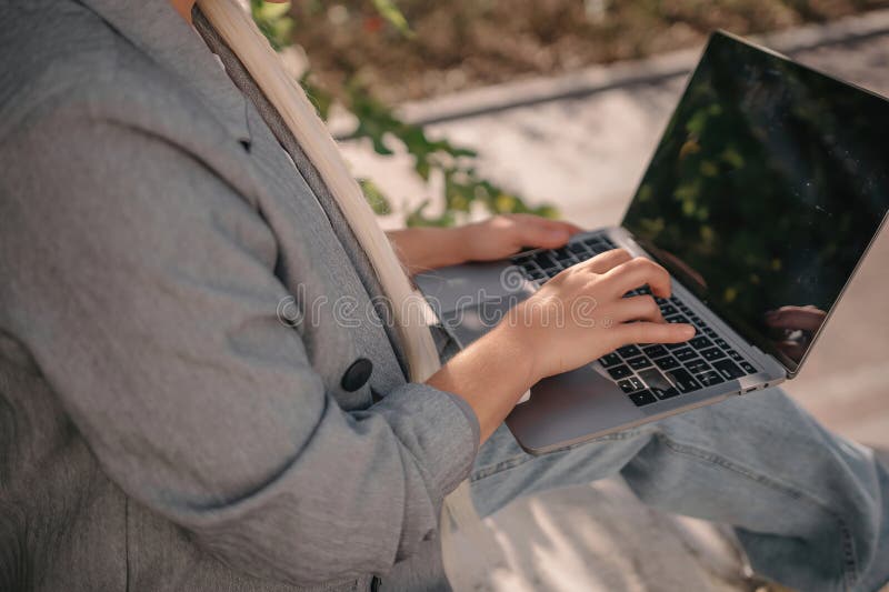 A Person is Sitting on a Bench with a Laptop Open in Front of Them ...