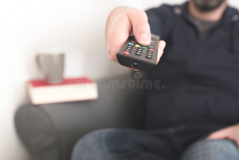 Person Sitting on Sofa Using TV Remote Control To Change Channels Stock ...