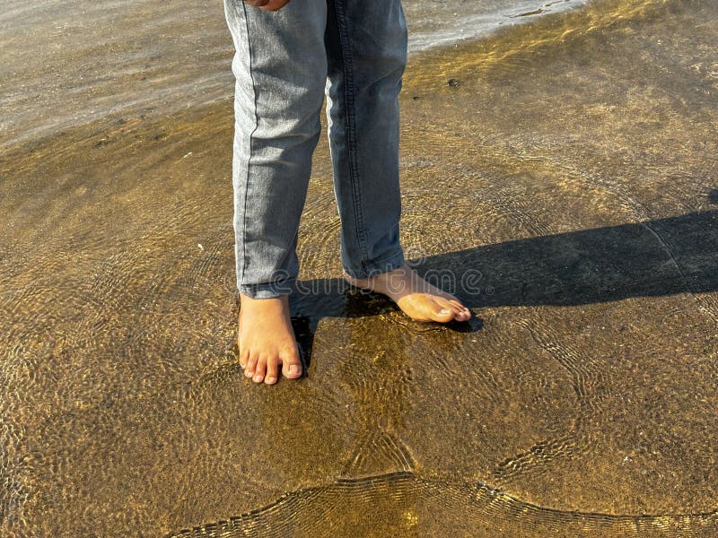 A Person is Standing Barefoot in the Sand with Their Feet in the Water ...