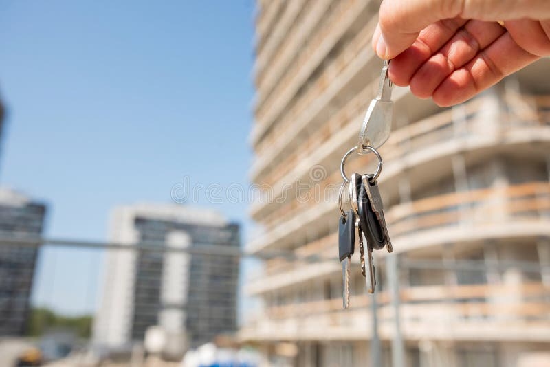 A Person is Standing while Holding a Set of Keys in Front of a Tall ...