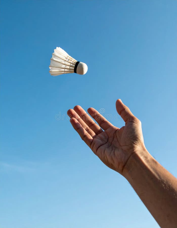 Person Throwing White Feather Shuttlecock Upward Against Blue Sky ...