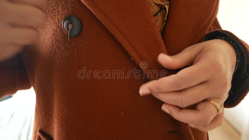 Person Using Lint Roller on a Rust-Colored Coat for Cleaning Purposes ...