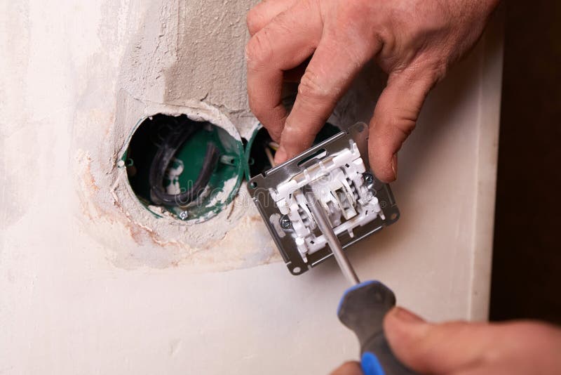 A Person is Using a Screwdriver To Install an Electrical Outlet on a ...