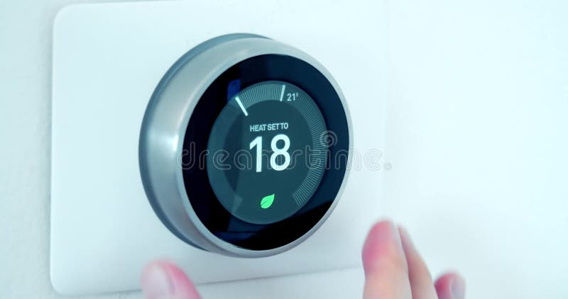 A Person Using a Smart Thermostat with a Hand Setting Lower the ...