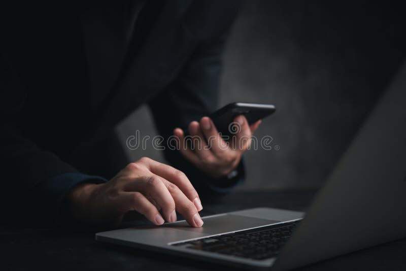 Person Using a Smartphone while Typing on a Laptop. Represents Modern ...