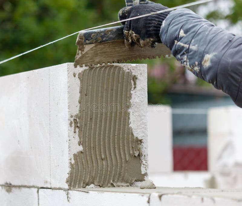 A Person is Using a Trowel To Apply a Layer of Cement To a Wall Stock ...