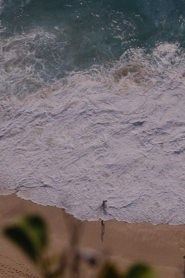A Person is Walking on the Beach in Front of a Large Wave Stock Photo ...