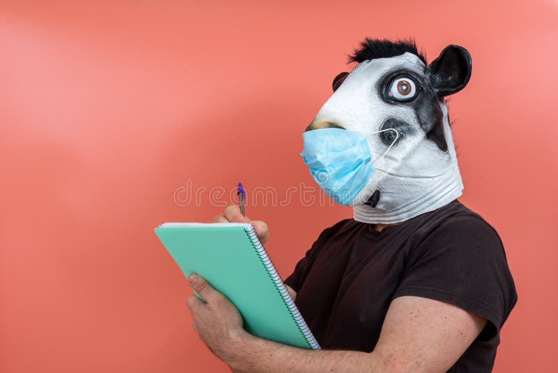 Person Wearing a Cow Mask and Surgical Mask Taking Notes with a Pen on ...