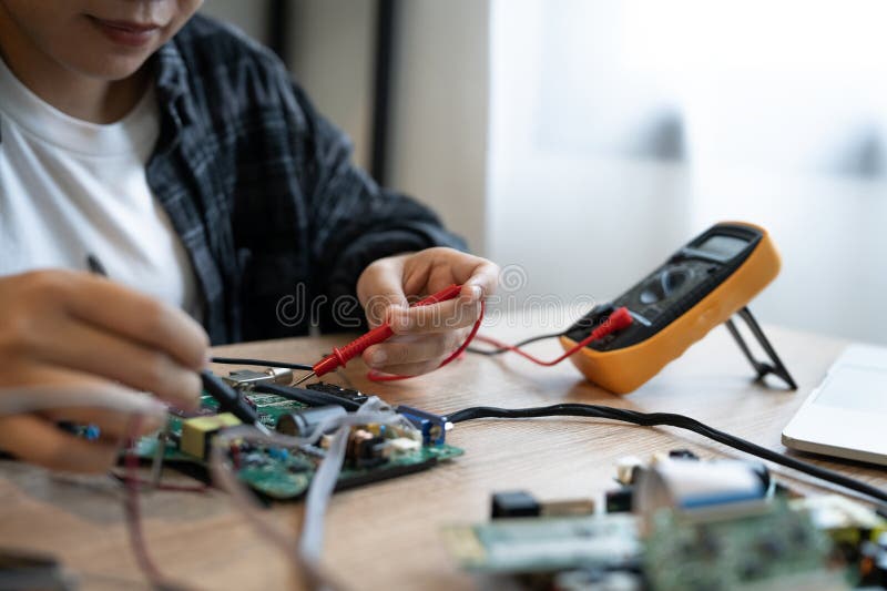 A Person is Working on a Circuit Board with a Multimeter. the Person is ...