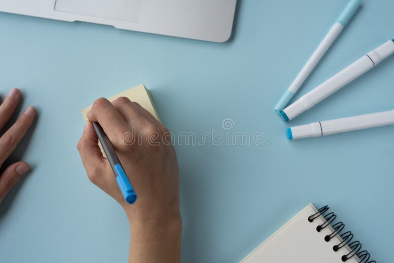 Person Writing on Sticky Notes on a Blue Desk with a Laptop, Notebook ...