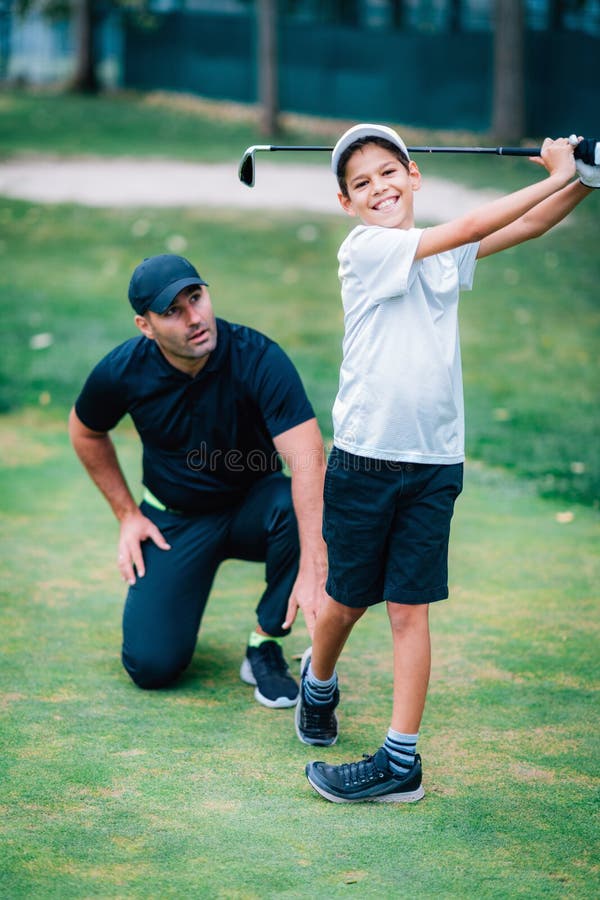 Personal Golf Lessons. Golf Instructor Adjusting Swing of a Young Boy ...