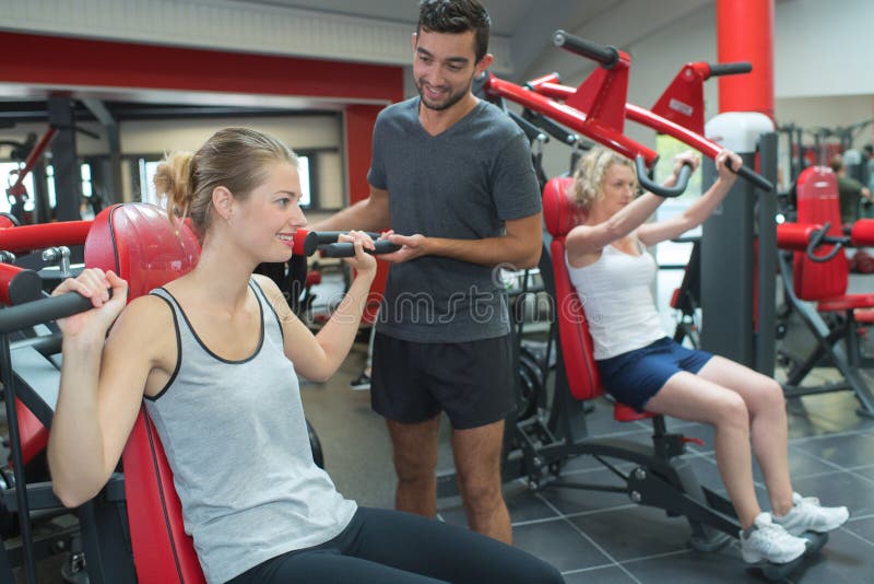 Personal Trainer Assisting Client on Chest Machine in Gym Stock Photo ...