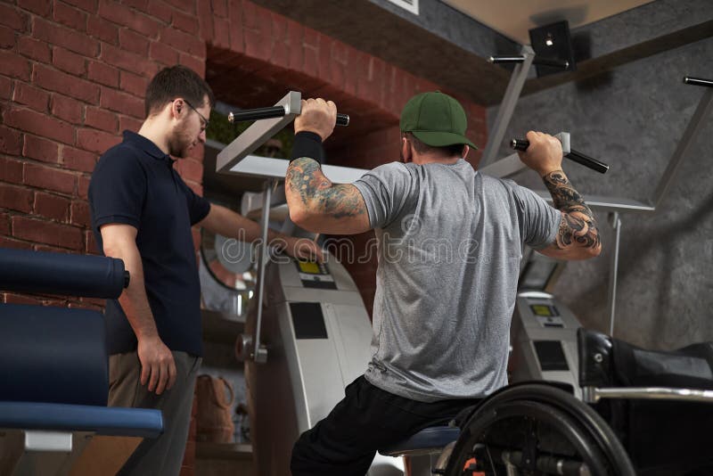 Personal Trainer Assisting New Gym Member on Exercise Machine Stock ...