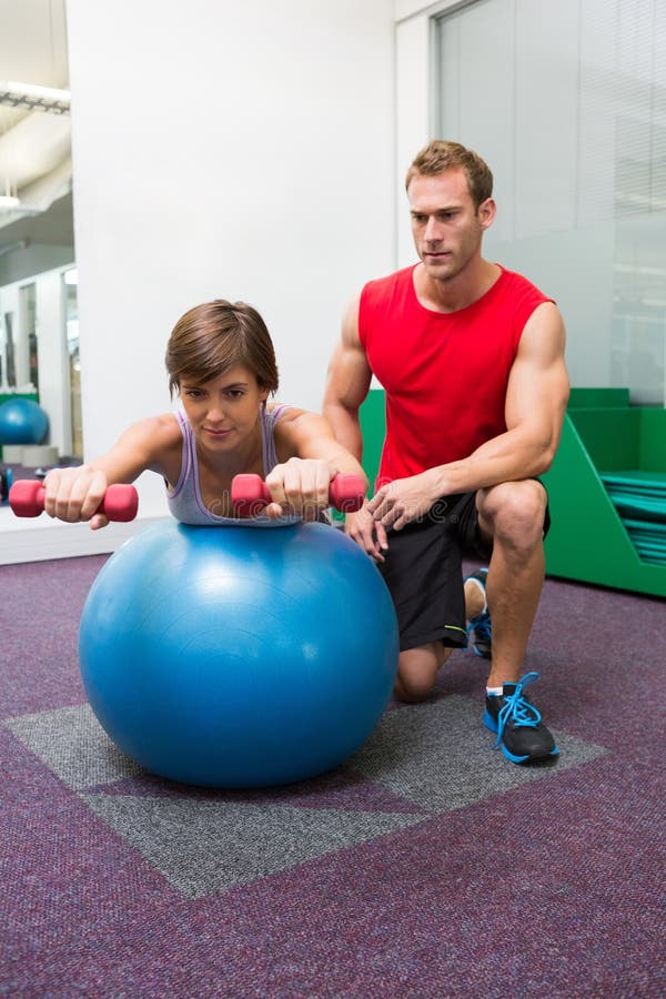 Personal Trainer with Client Lifting Dumbbells on Exercise Ball Stock ...