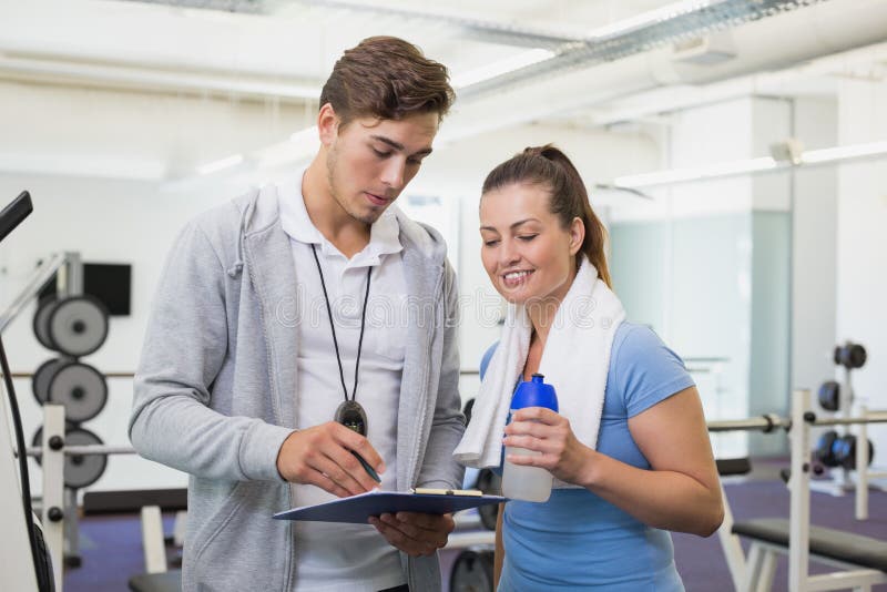 Personal Trainer and Client Looking at Clipboard Together Stock Photo ...