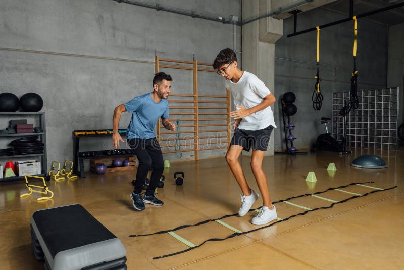 Personal Trainer Encouraging Boy during Circuit Training Routine at Gym ...