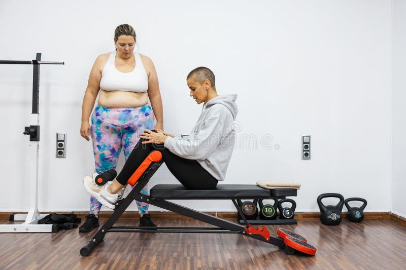 Personal Trainer Guiding Client through Abdominal Exercises on Bench in ...