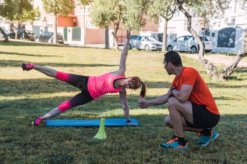 Personal Trainer Guiding a Woman Doing Exercises Outdoors Stock Photo ...