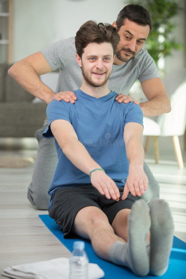 Personal Trainer Guiding Young Man during Floor Exercises Stock Photo ...