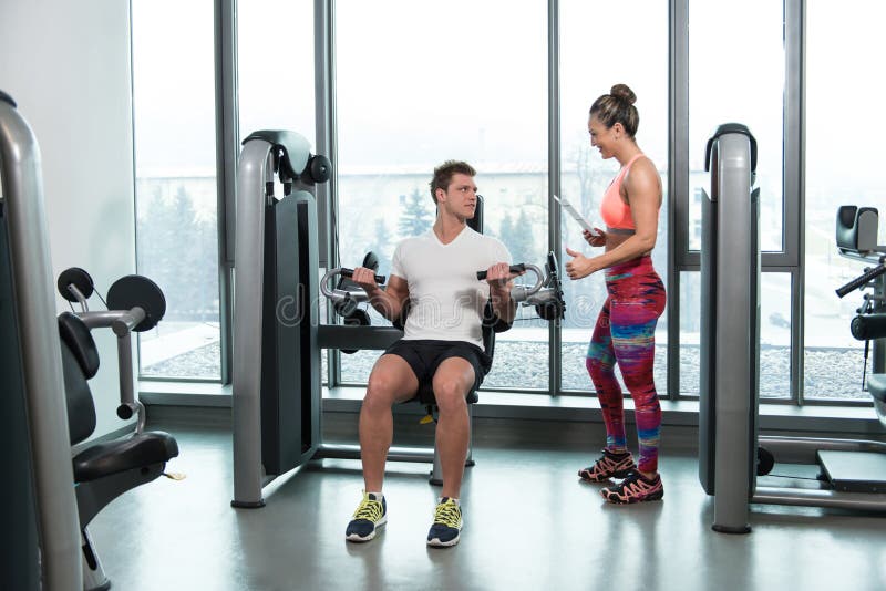 Personal Trainer Helping Client in Gym Stock Image - Image of ...