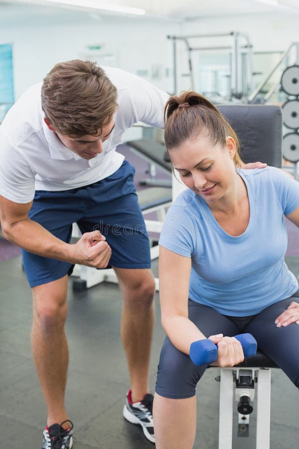 Personal Trainer Helping Client Lift Dumbbell Stock Photo - Image of ...