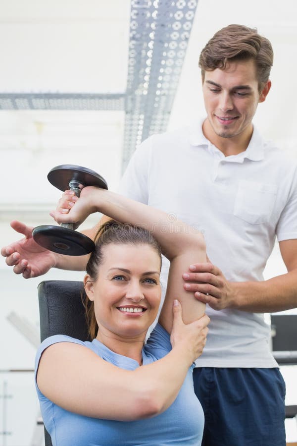 Personal Trainer Helping Client Lift Dumbbell Stock Photo - Image of ...