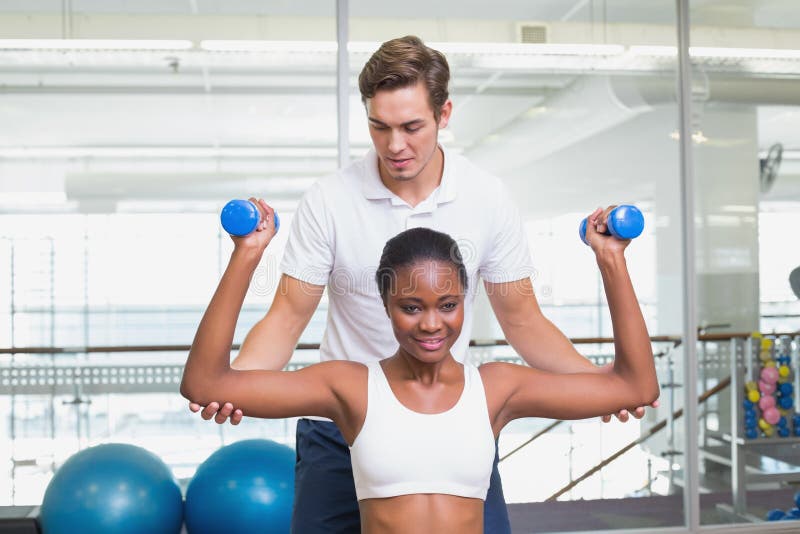 Personal Trainer Helping Client Lift Dumbbells on Exercise Ball Stock ...