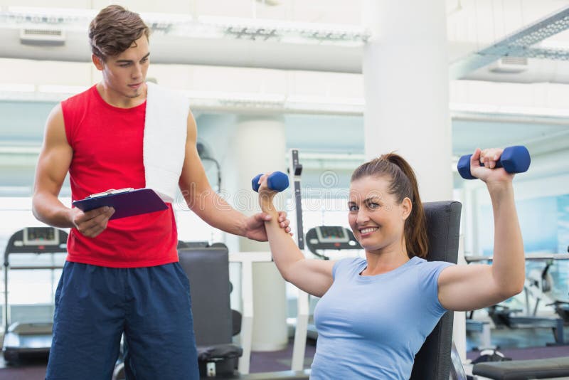 Personal Trainer Helping Client Lift Dumbbells Stock Image - Image of ...