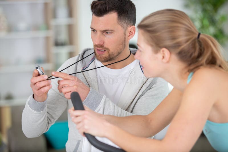 Personal Trainer Helping Female Client on Elliptical Machine Stock ...