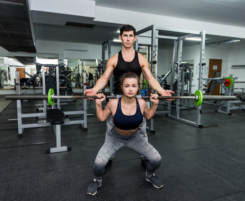 Personal Trainer Helping Work with Barbell in Gym Stock Photo - Image ...