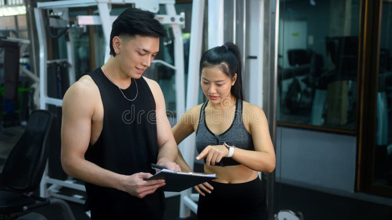 Personal Trainer and His Client Reviewing Workout Progress in the Gym ...