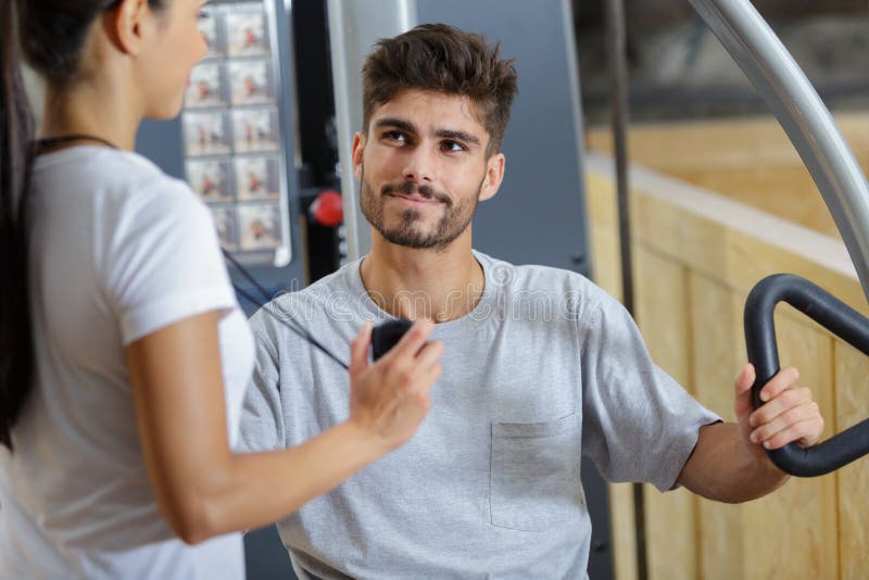 Personal Trainer Showing Time To Man Using Gym Machine Stock Image ...