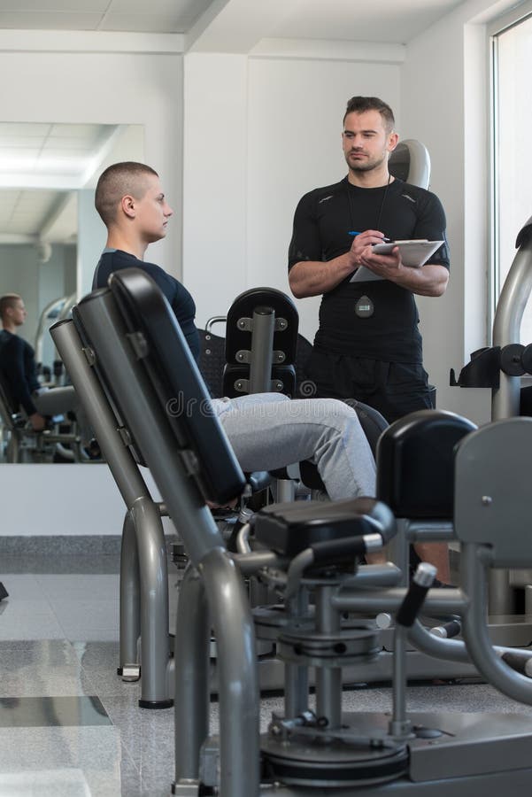 Personal Trainer Takes Notes while Man Exercising Legs Stock Image ...