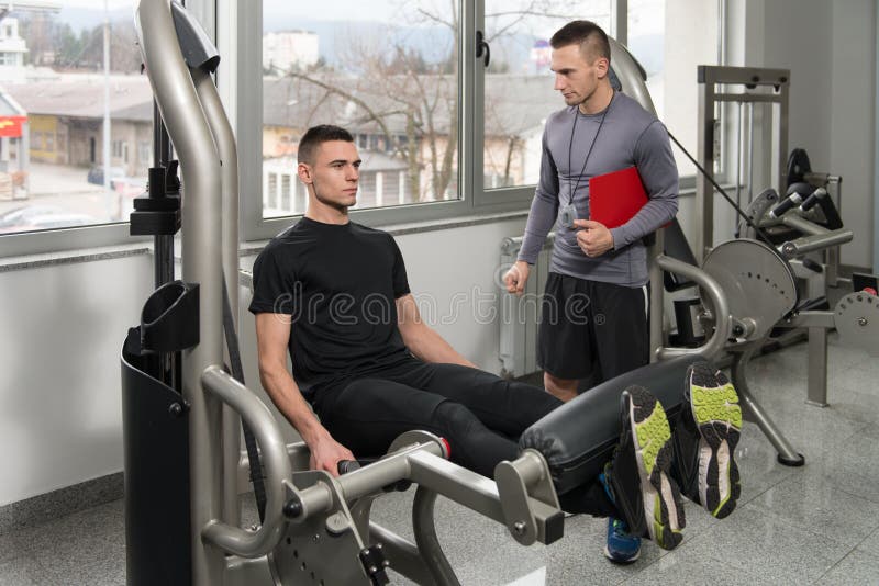 Personal Trainer Takes Notes while Man Exercising Legs Stock Photo ...