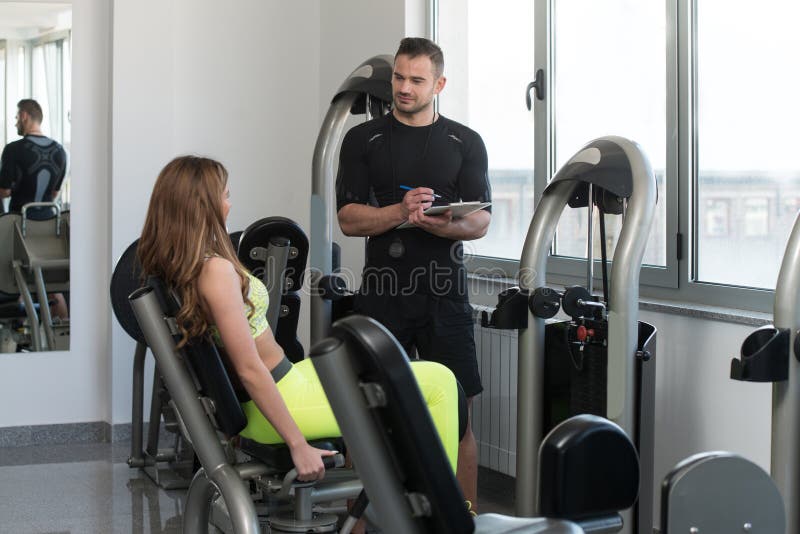 Personal Trainer Takes Notes while Woman Exercising Legs Stock Image ...