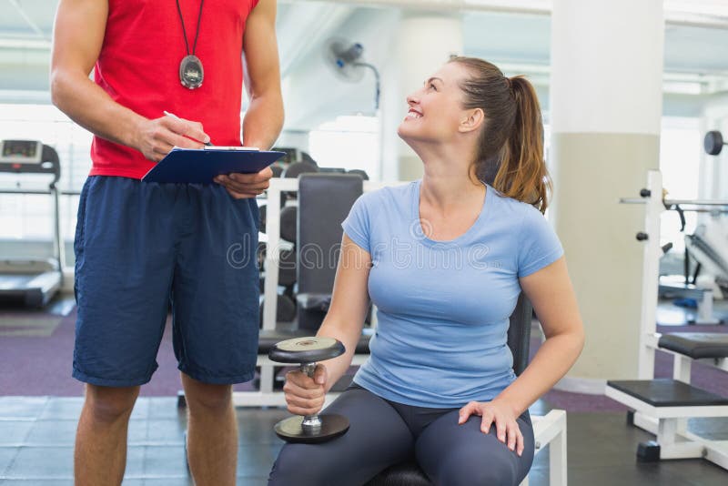Personal Trainer Working with Client Holding Dumbbell Stock Photo ...