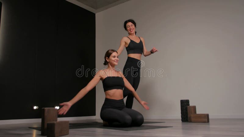 A Personal Yoga Instructor Helps a Young Woman To Do an Exercise. Yoga ...