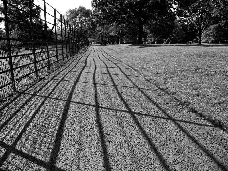 Perspective View of Long Iron Fence Casting a Shadow on a Asphalted ...