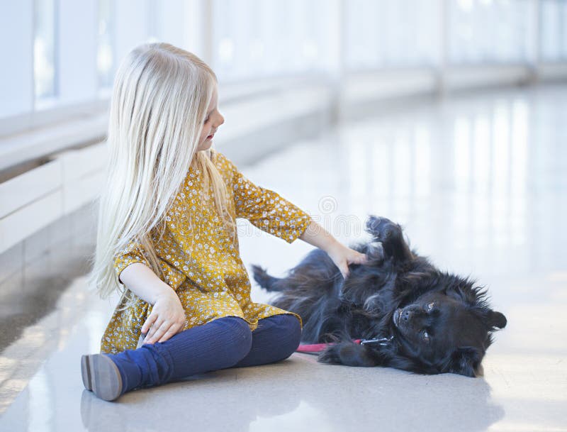 Petite Fille De Sourire S'asseyant Sur Le Plancher Et Tapoter Le Chien ... Petite Fille De Sourire S'asseyant Sur Le Plancher Et Tapoter Le Chien ...