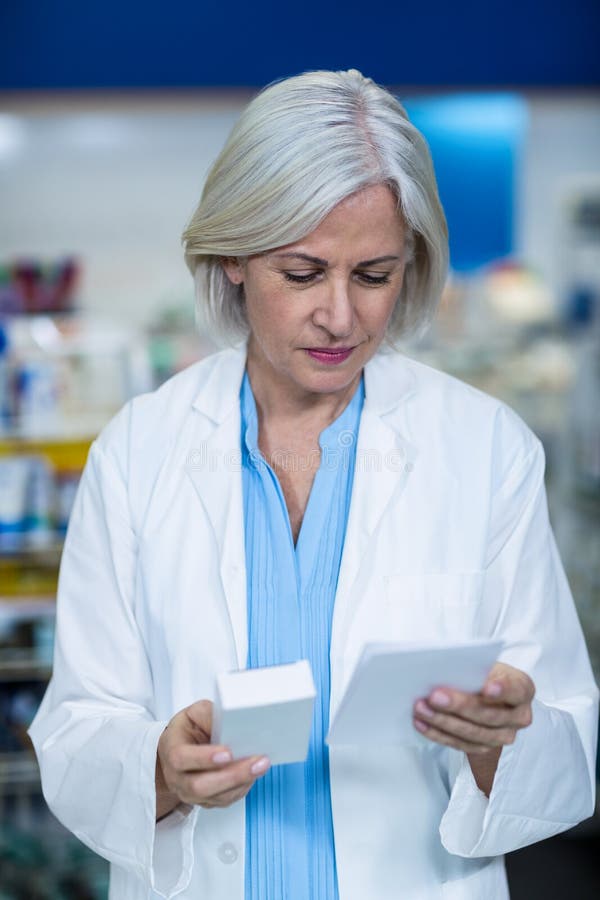 Pharmacist Holding Medicine while Checking Prescription Stock Photo ...