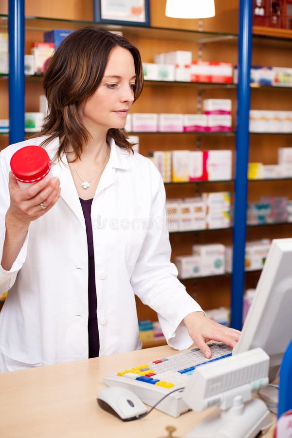 Pharmacist Holding Pill Bottle while Using Computer at Counter Stock ...