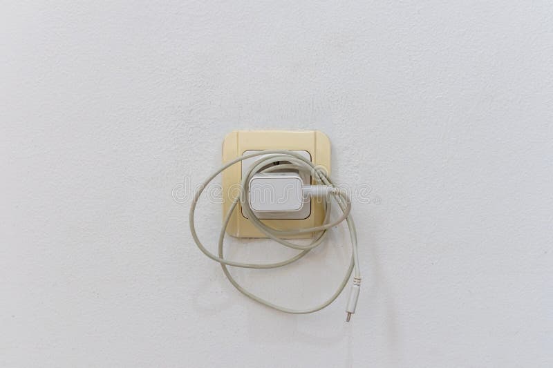 The Phone Charger is Plugged into the Electrical Power Socket on Wall ...