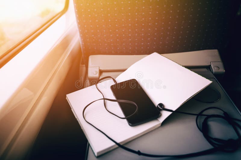 Phone with Headphones on Notebook at Window Light in Train. Smartphone ...