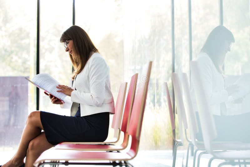 Businesswoman Reading Document while Sitting at Office Stock Photo ...
