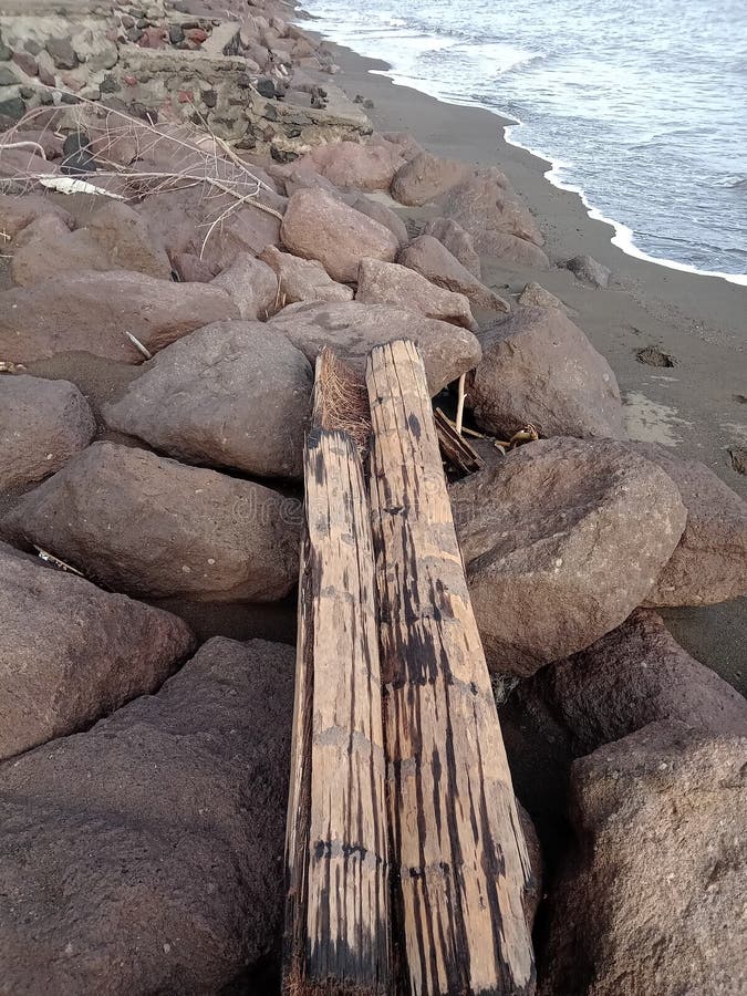 The Photo of a Log Lying on a Rock Washed Up by the Waves on the Beach ...