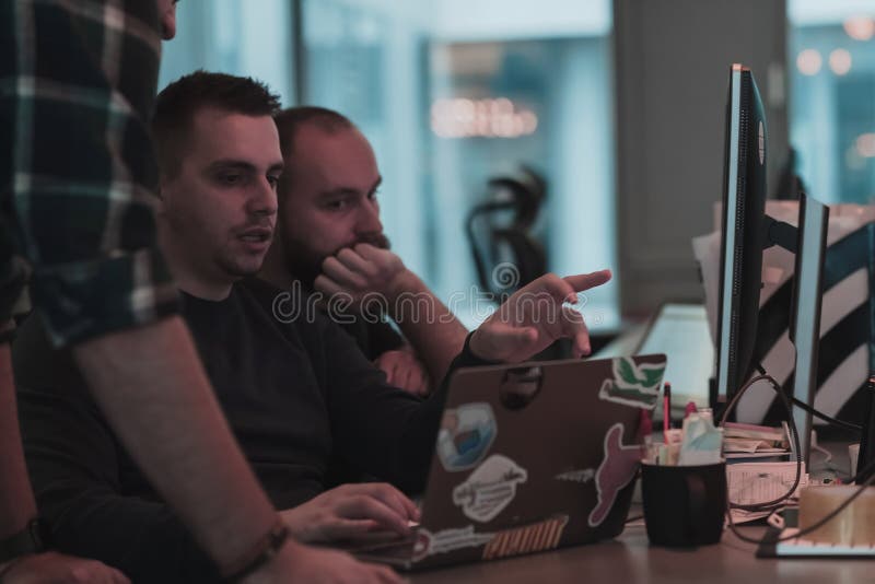 A Photo of Three Men Staring Intently at a Computer while Sitting in a ...