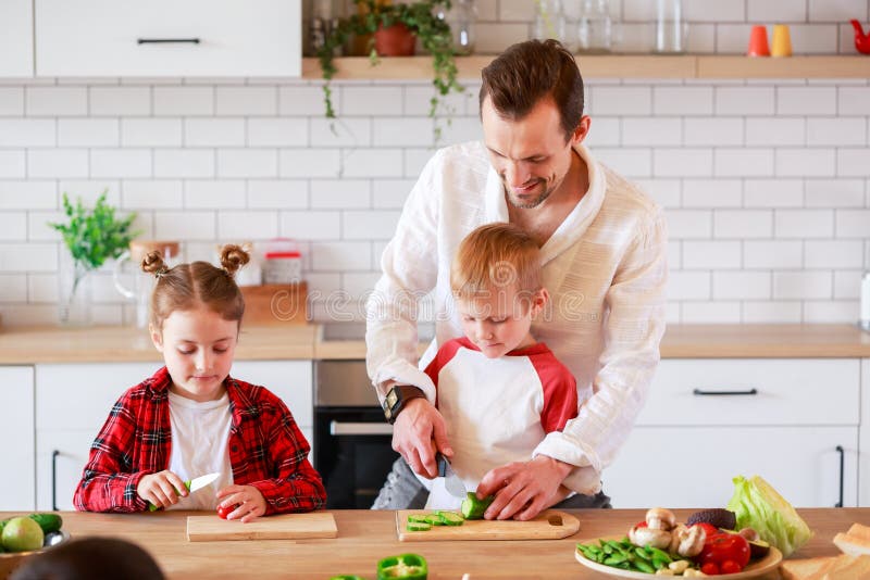 Photo of Young Father with Daughter and Son Cooking at Table Stock ...
