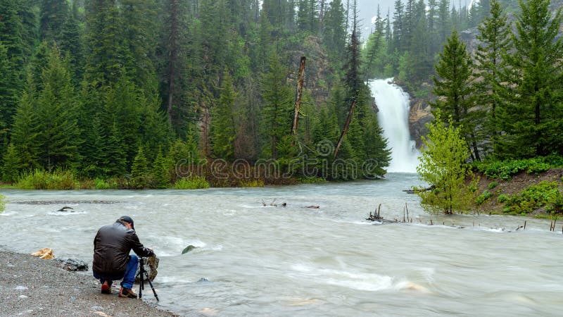 Photographer in Glacier National Park in the Rain with Waterfall Stock ...