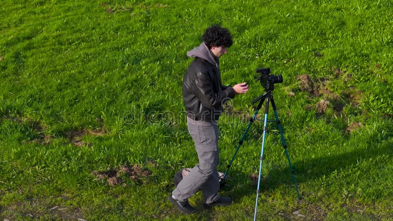 Photographer Man Setting Up a Camera Tripod in the Grass Field Stock ...