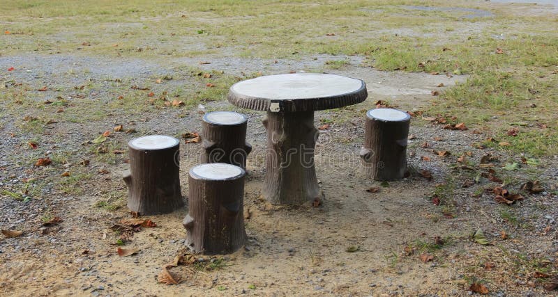 A Photography of a Table and Four Stools in a Field, Pole and Stump ...